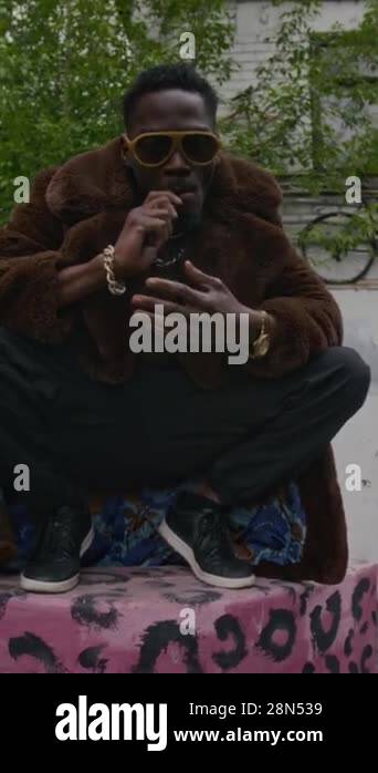 Vertical full portrait of cool Black male rapper in brown fur coat and ...