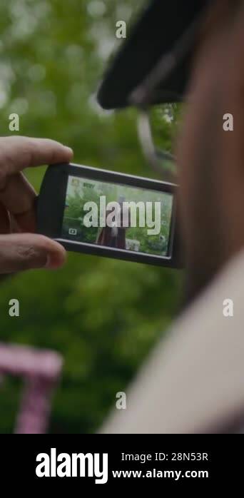 Vertical over shoulder shot of male videographer recording video of ...