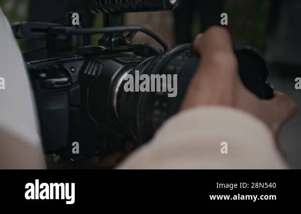 Close-up of hands of anonymous cameraman adjusting lens on modern ...