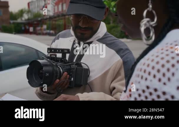 Tilt shot of young male videographer with modern camera discussing ...
