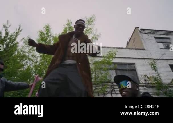 Low angle handheld shot of charismatic and cool Black rapper in fur ...