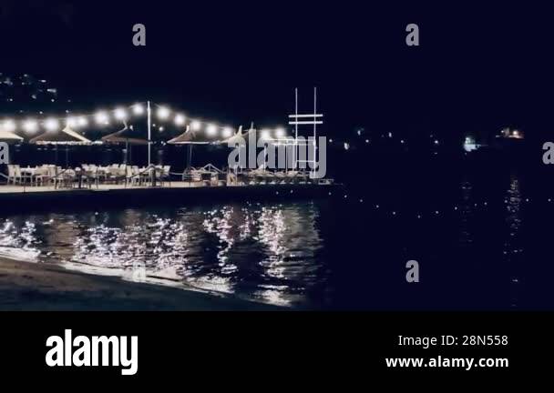 Charming waterside dining area with string lights reflecting on the ...