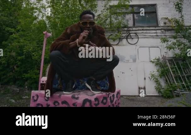 Full portrait of cool Black male rapper in brown fur coat and ...