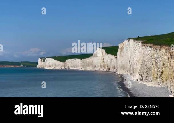 Majestic white chalk cliffs tower above a calm blue sea, creating a ...