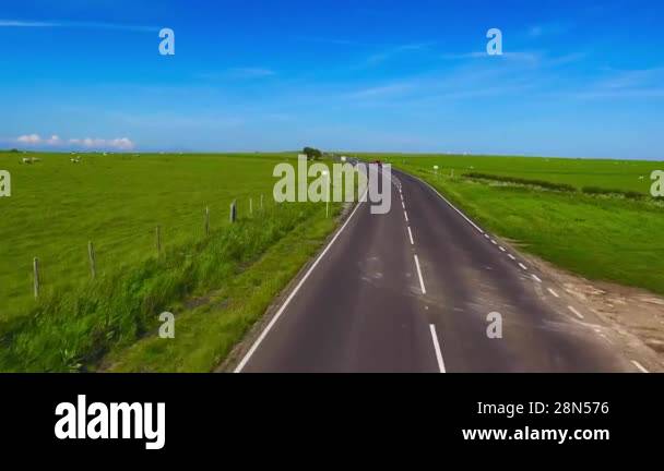 English countryside road stretches through vibrant green hills under a ...