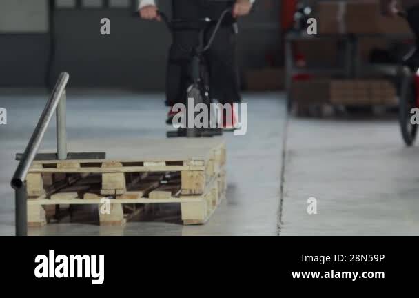 Midsection slowmo shot of anonymous BMX stunt rider jumping on wooden ...