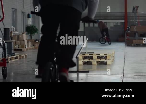 Full back shot of young male BMX rider on bike cycling up steel rail ...