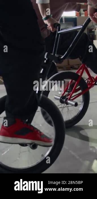 Vertical side tracking slowmo shot of two unrecognizable BMX riders ...
