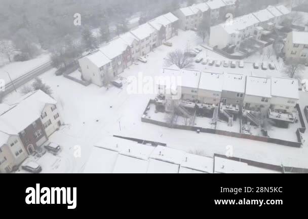 Blizzard, residential homes and trees during winter snowfall. Lone cars ...
