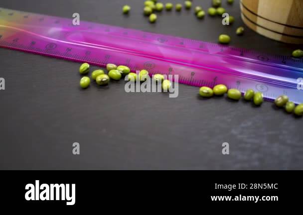 Legumes: Green mung beans on a black surface next to a transparent pink ...