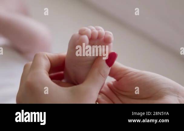 Close-up of a young mothers hands massaging a babys foot. Newborn care ...