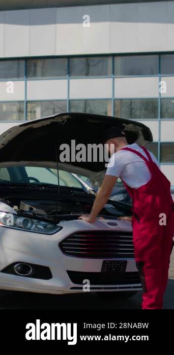 Car service worker checks vehicle oil on parking lot near car service ...