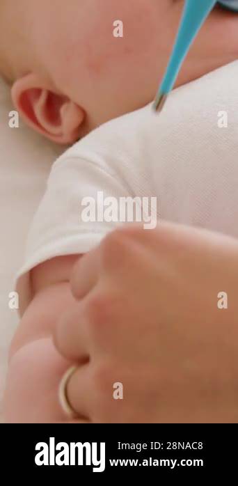 Close-up of a mother taking her babys temperature with a digital ...