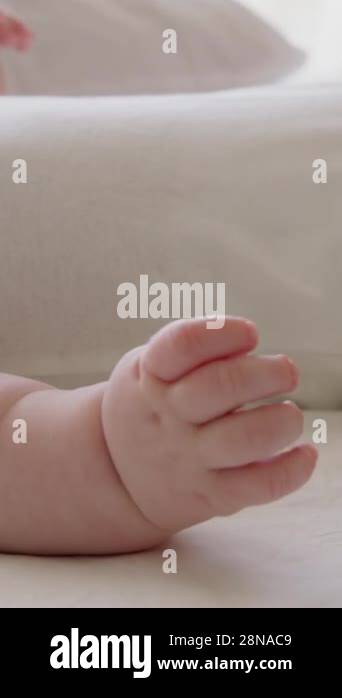 Side view of a baby boy in a white bodysuit lying on his back in a ...