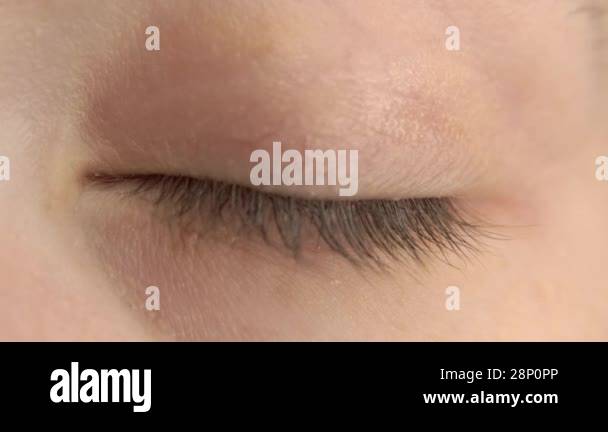 A close-up video of a woman's closed eye slowly opening, showcasing ...
