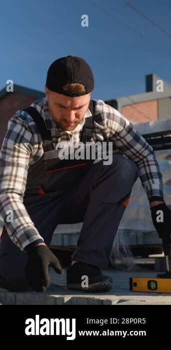 Close-up of a construction worker using a rubber hammer and level tool ...