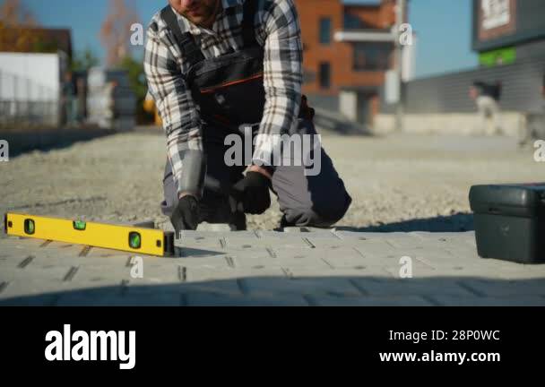 Close-up of a construction worker using a mallet to adjust paving ...