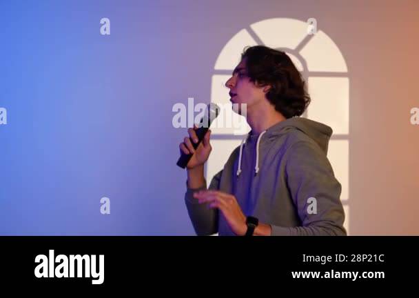 Person with mic on colorful studio background. Portrait of man singing ...