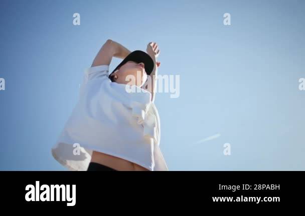 Flexible lady training outdoors raising hands to clear blue sky closeup ...