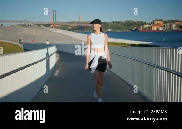 Sporty lady walking urban bridge at serene summer morning. Calm ...