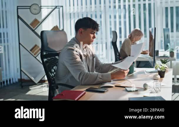 Confused man employee examining papers working on project task at ...