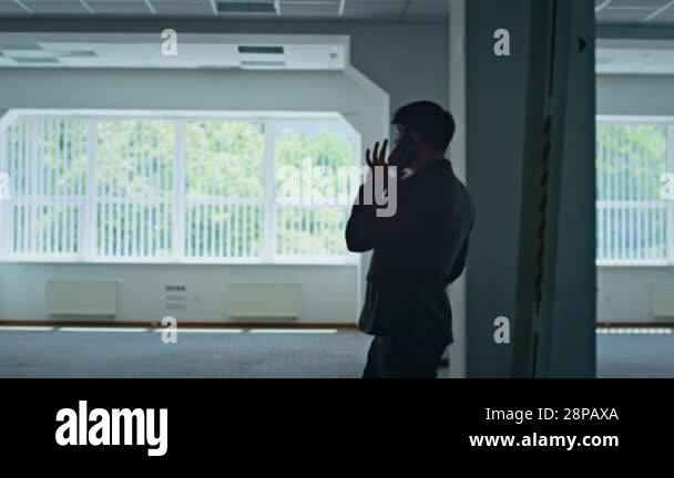 Emotional employee having cellphone call going at contemporary building ...