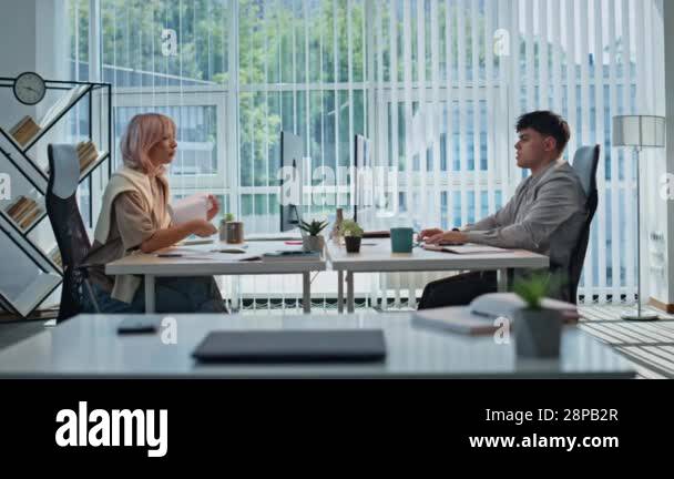 Office workers sitting table solving tasks at panoramic interior. Tired ...