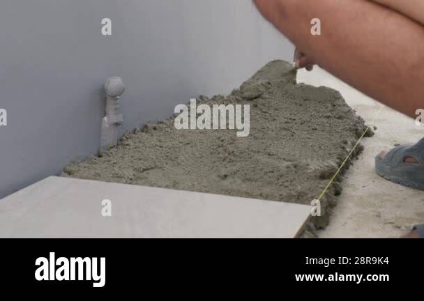 Close-up of a worker smoothing gray mortar with a tool, ensuring the ...