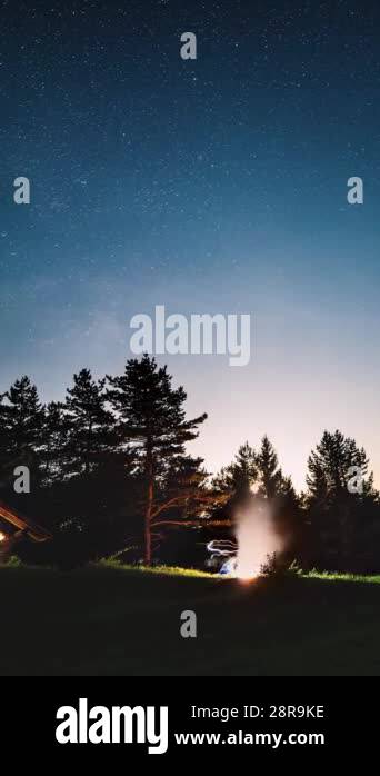Friends sitting by campfire in forest nature under starry night sky ...