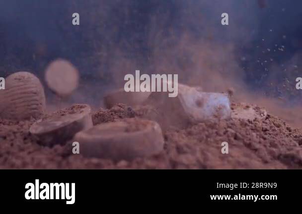 Chocolate pralines falling in cocoa powder on black background ...