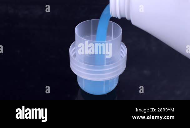 Blue liquid detergent flowing from the bottle into the container on ...