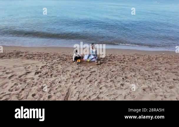 aerial view of toddler baby girl playing sand toy with mother on the ...