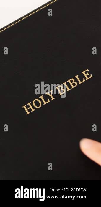Finger is pointing on golden holy bible text. Vertical video. Top view ...