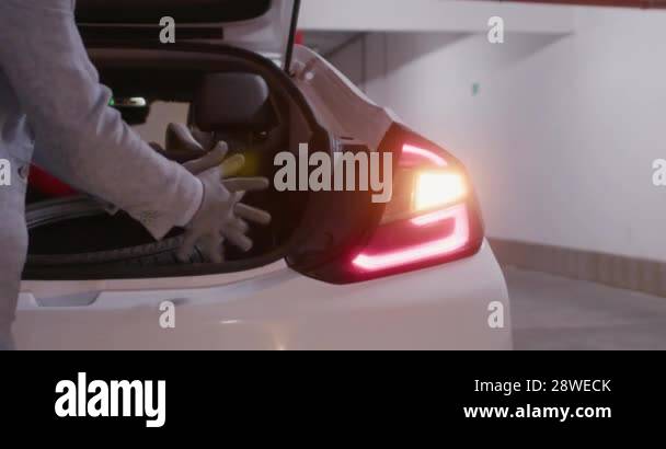 Driver puts on gloves and takes tire out of car trunk. Vehicle ...