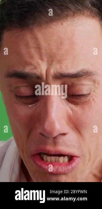 Close up of a sad man crying desperately looking at camera, on a green ...