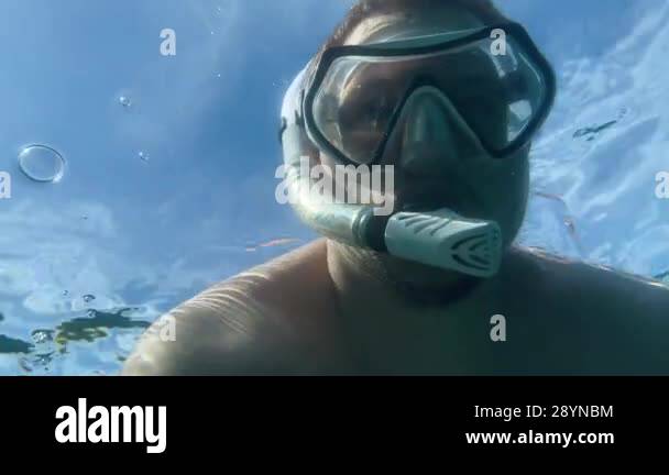 person wearing a swimming mask with a breathing tube and snorkeling in ...