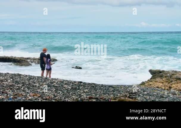 a loving couple stands on the coast and looks at the raging waves of ...