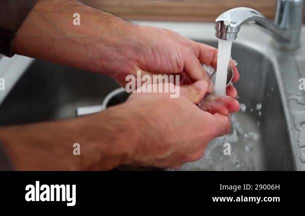 A person diligently and carefully cleaning numerous utensils under a ...