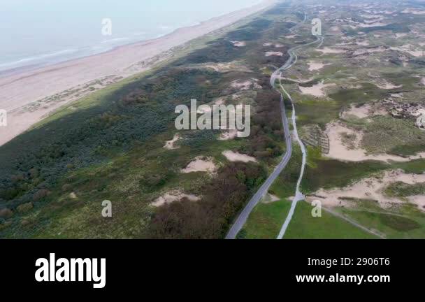 Aerial view of a coastal landscape with lush greenery, sandy dunes, and ...