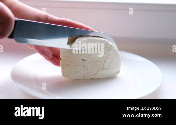 Using a steel knife, we cut white cheese on plate. High quality 4k ...