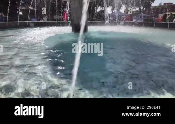 Sparkling water flows from a modern fountain in a vibrant public square ...