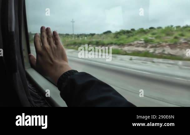 Hand reaching out of a bus window while traveling through scenic ...