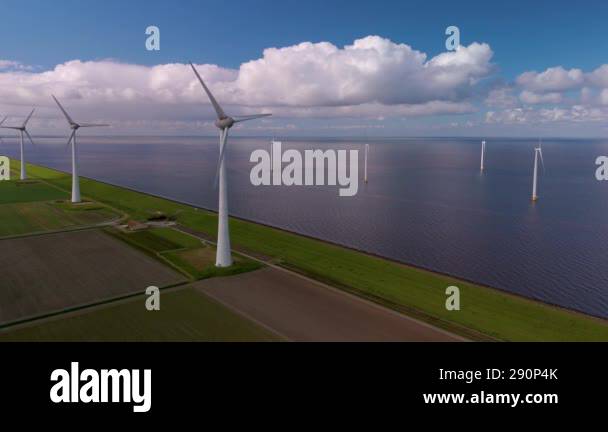 Witness the stunning array of wind turbines standing tall against the backdrop of a clear blue ...