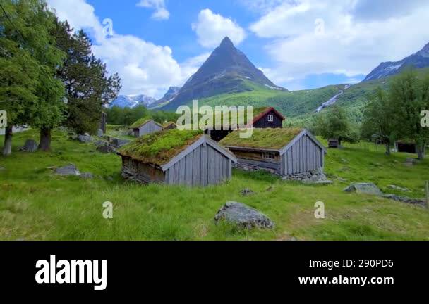Discover stunning mountain views featuring traditional Norwegian cabins with grass roofs nestled ...