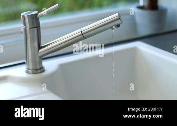 Modern kitchen with white sink and stainless steel faucet, blurred ...