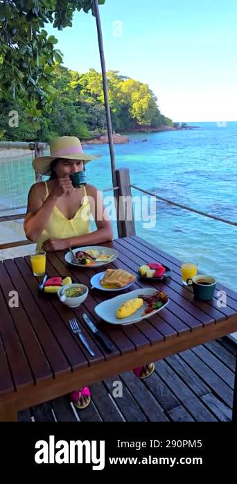 A woman Enjoy a delightful brunch with stunning views in Koh Kood Island, Thailand. This ...