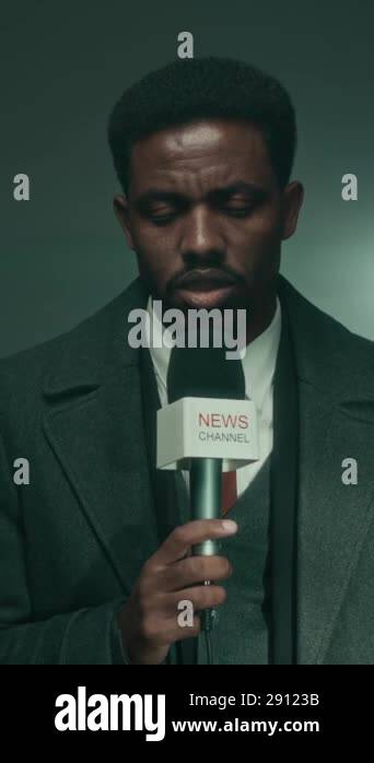 Vertical medium low-key shot of young Black male correspondent wearing ...