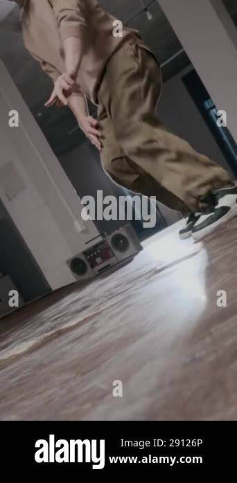 Vertical ground level shot of skilled Caucasian male zoomer breaking in ...