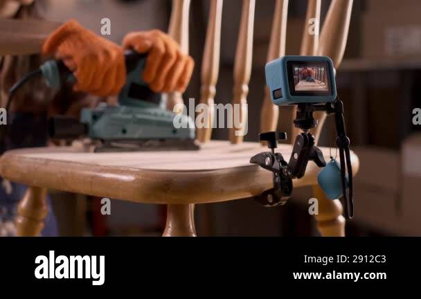 Female carpenter in workshop using electric sander to restore old ...