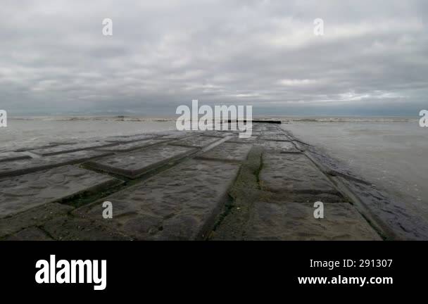 timelapse of a tranquil seaside view with algae-covered rocks leading ...